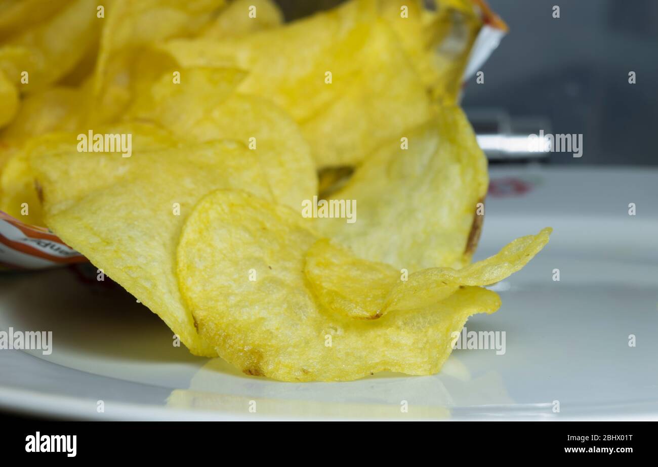 Opened chips bag and porcelain plate underneath Stock Photo - Alamy