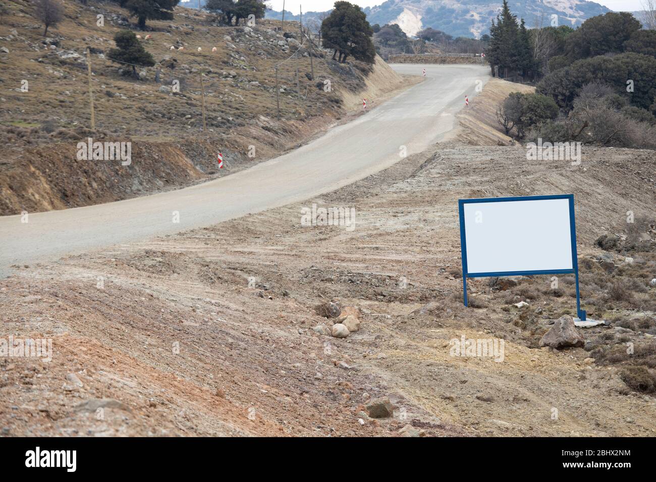 White curved advertising sign. There are olive trees in the background ...