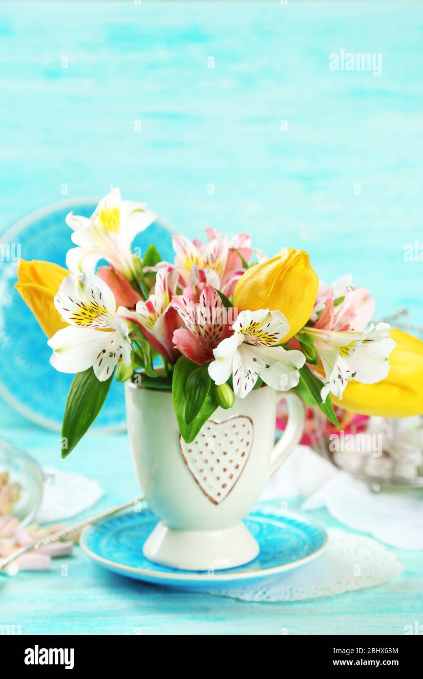Beautiful flowers in cup, on color wooden background Stock Photo - Alamy