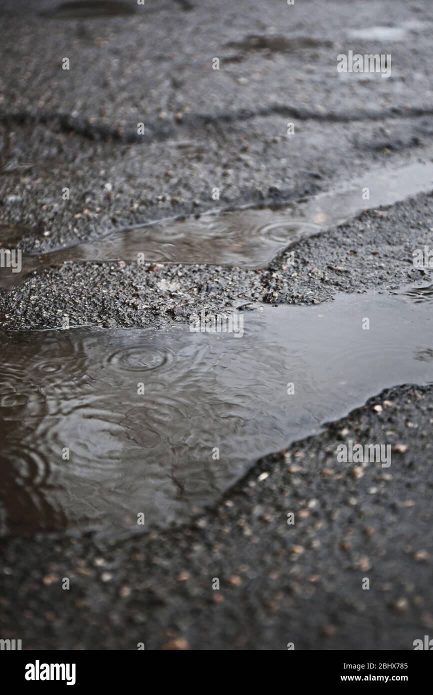 Holes with puddles on damaged asphalt background Stock Photo - Alamy