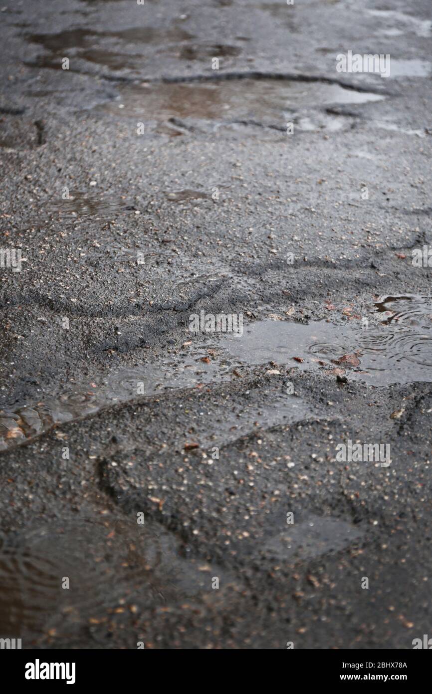 Holes with puddles on damaged asphalt background Stock Photo - Alamy