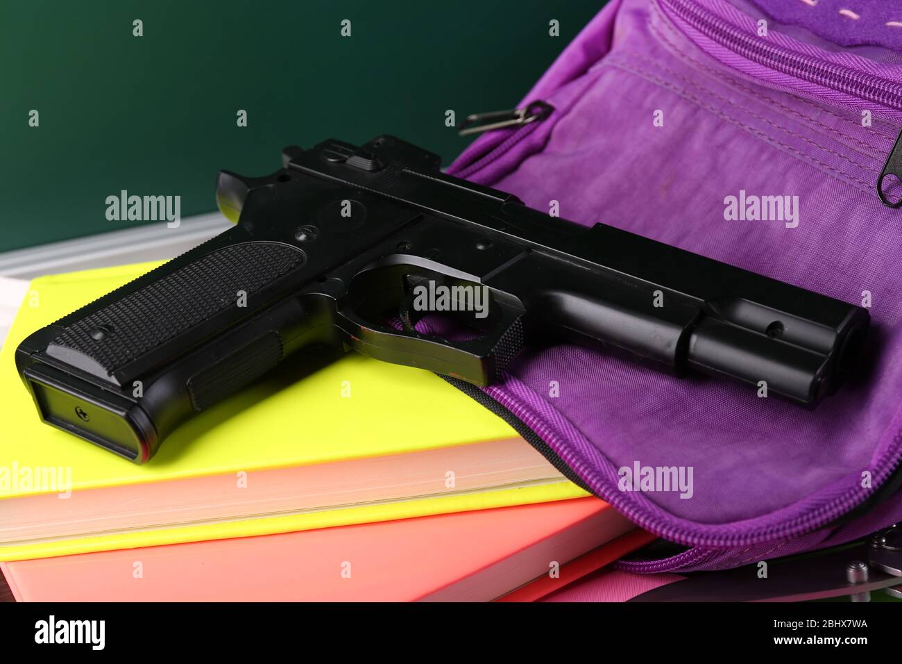 Gun in school backpack close-up, on blackboard background Stock Photo ...