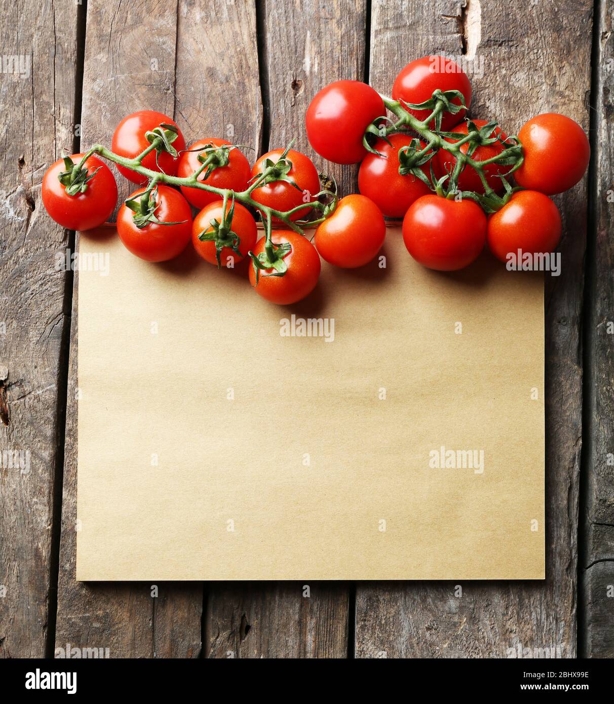 Sheet of paper with cherry tomatoes on rustic wooden surface background ...