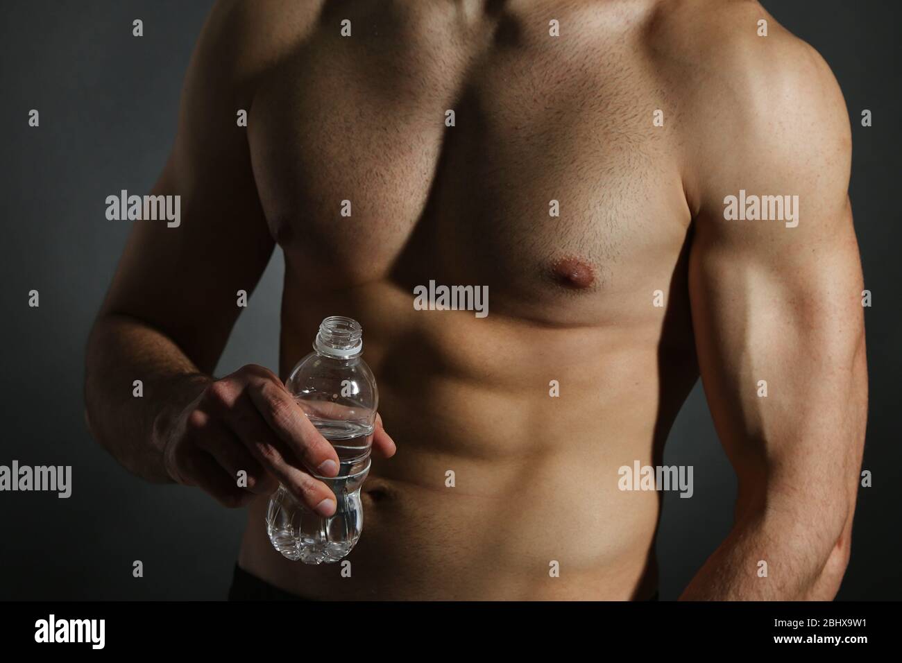 Muscle young man holding bottle of water on black background Stock ...