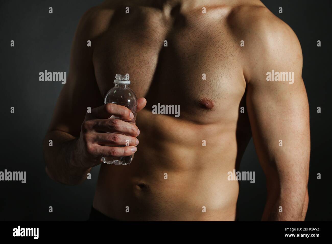 Muscle young man holding bottle of water on black background Stock ...