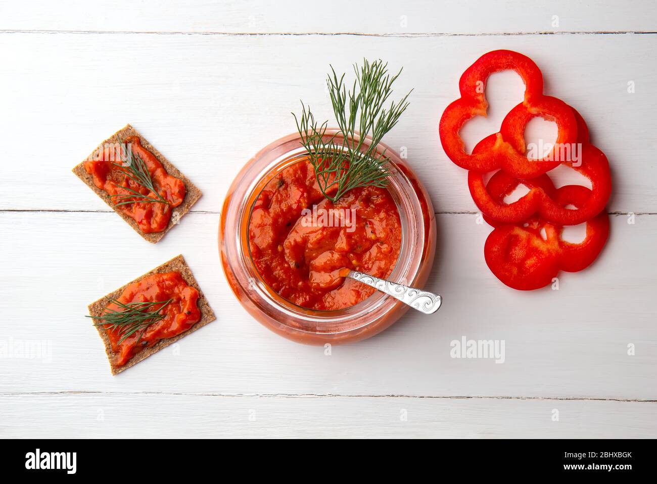 Balkan snack ajvar in a jar and on bread rolls on a white background ...