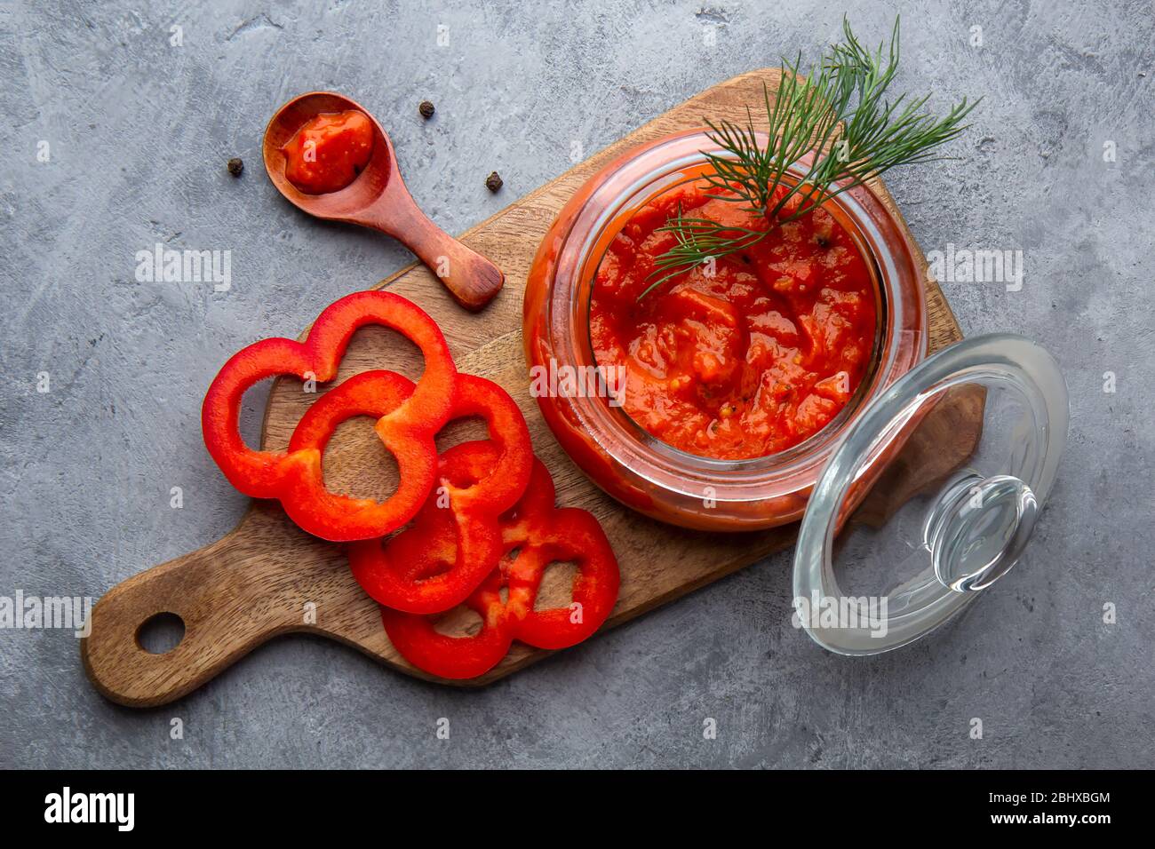 Glass jar with ajvar, lutenitza on a gray background. Balkan cuisine ...