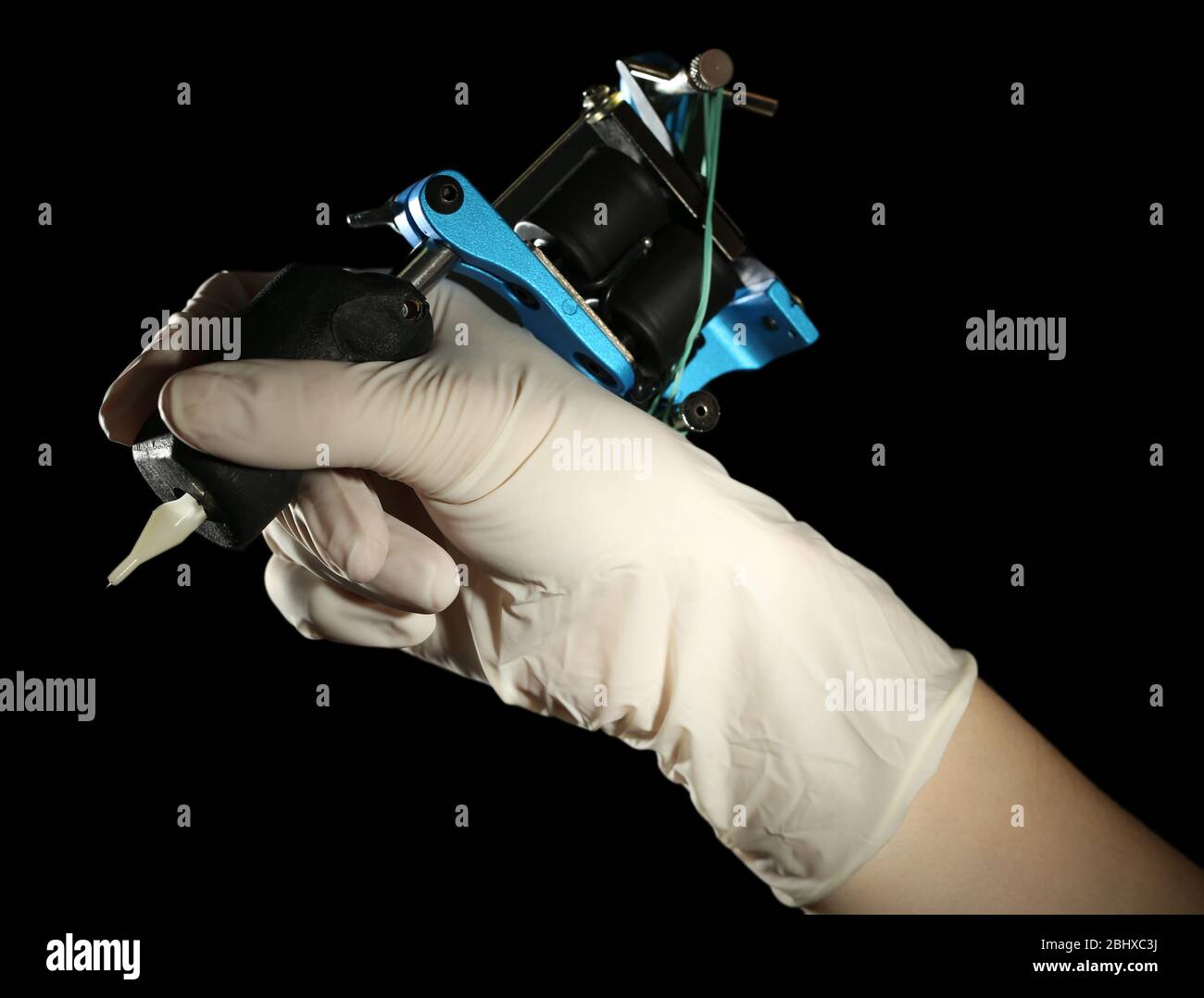 Tattoo artist holding tattoo machine, on dark background Stock Photo ...
