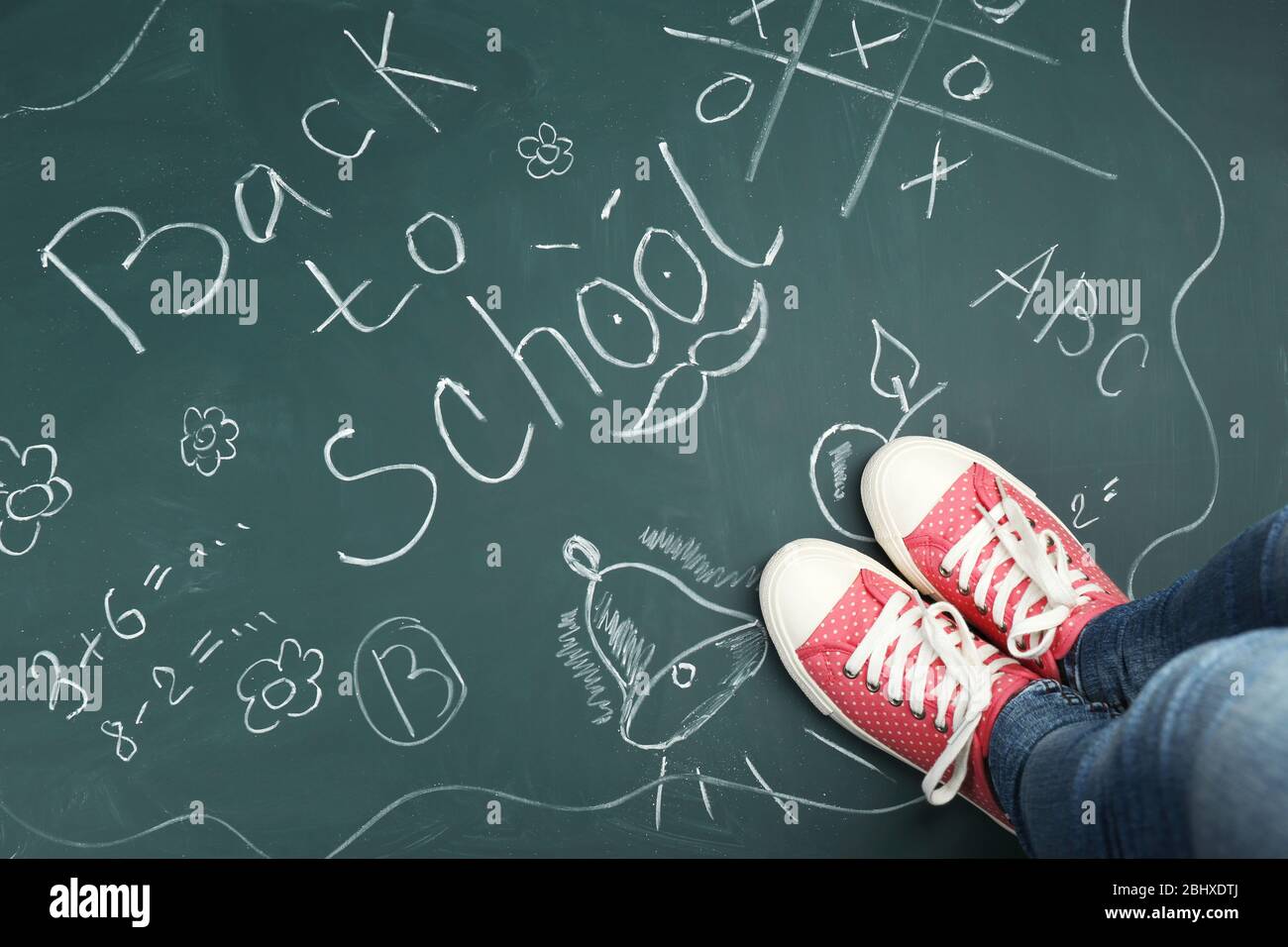 Female feet on blackboard background with inscriptions and sketches ...