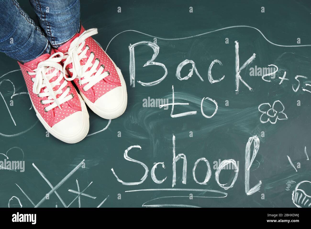 Female feet on blackboard background with inscriptions and sketches ...