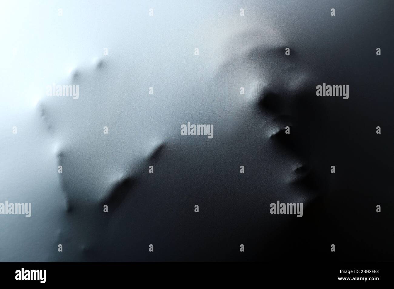 Screaming human face with hand pressing through fabric as horror ...