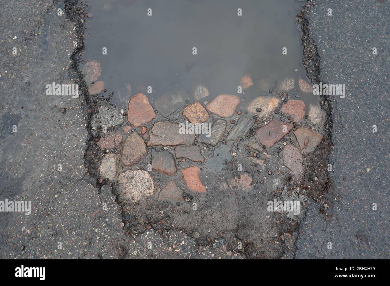 Pot hole revealing old stone road below modern asphalt Stock Photo - Alamy