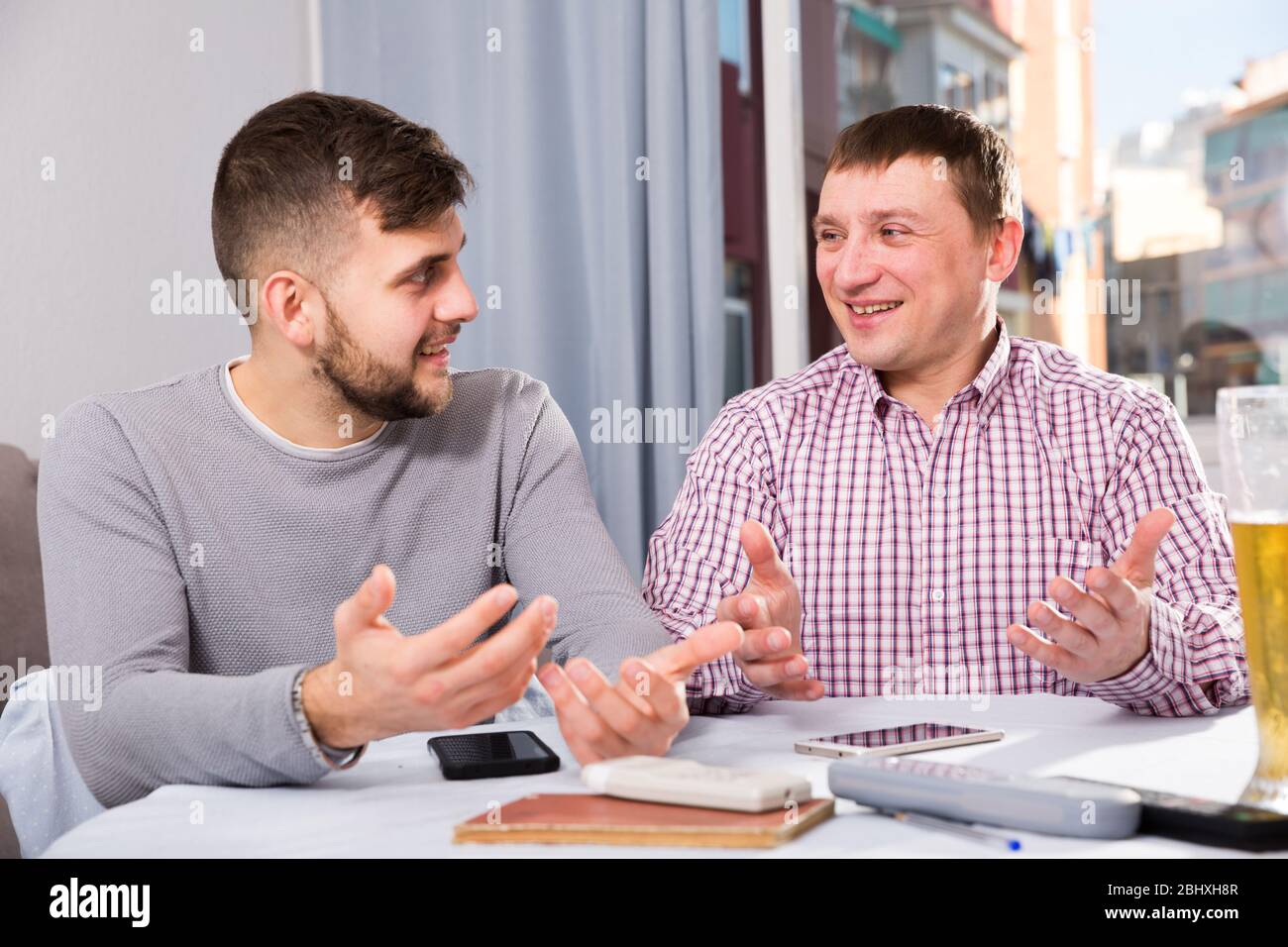 Two cheerful men enjoying conversation at home table Stock Photo - Alamy