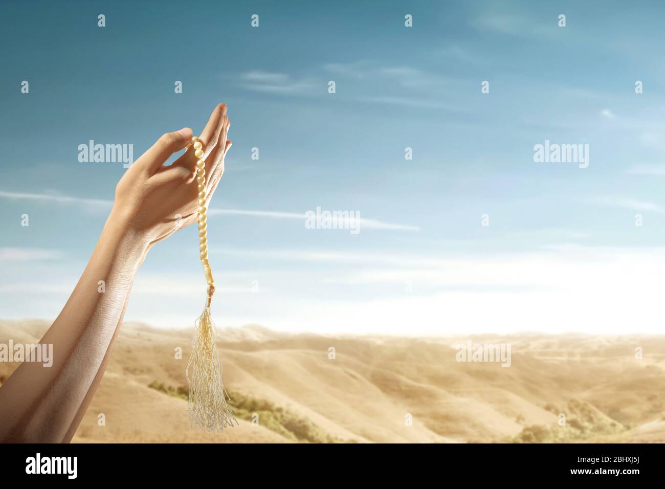 Muslim man praying with prayer beads on his hands with a blue sky ...