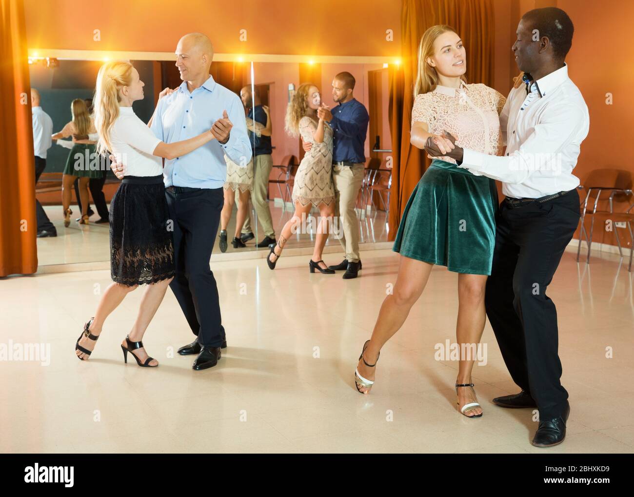 Young positive people dancing together slow ballroom dances in pairs ...