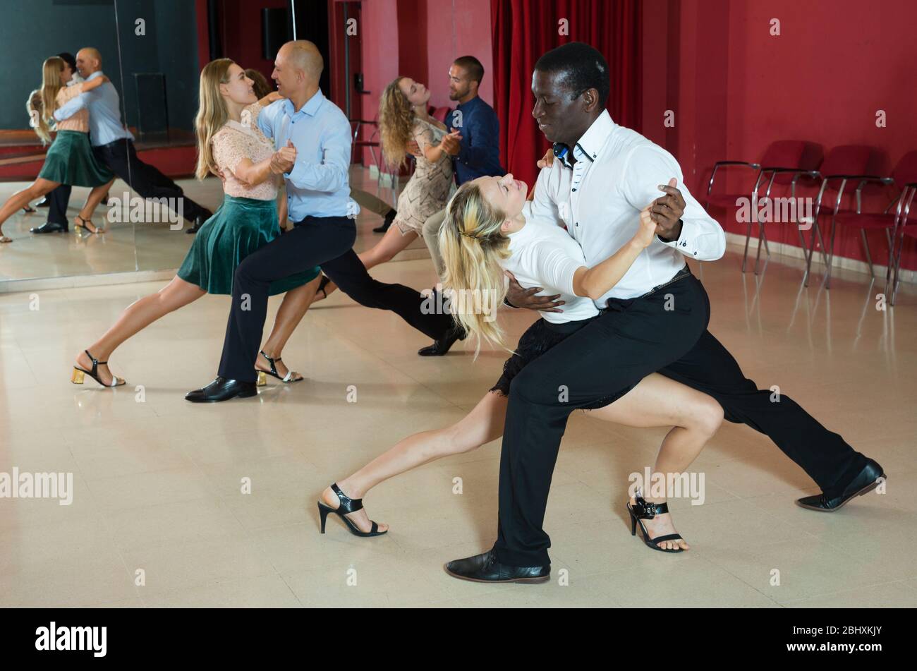 Young positive people dancing Argentine tango in pairs in studio Stock ...