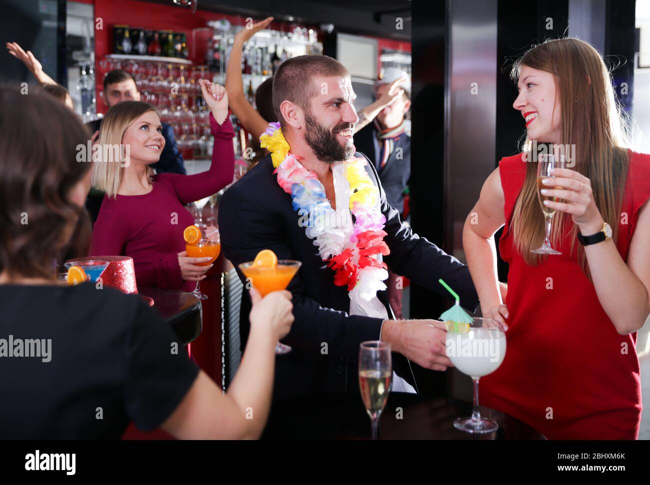 Young man with female colleague enjoying corporate party in Hawaiian ...