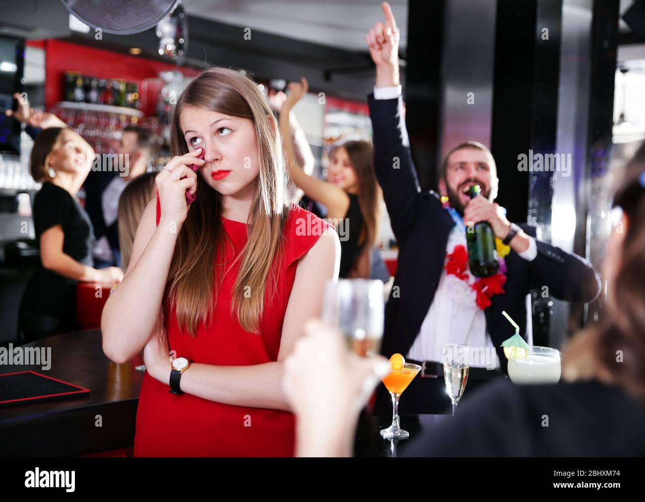 Offended young woman on background with drunk man on party in nightclub ...
