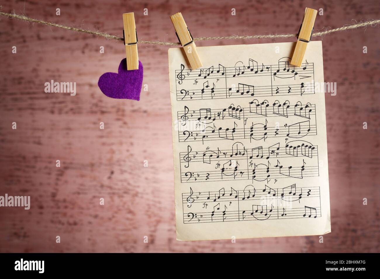 Bright heart and music sheet hanging on rope on wooden background Stock ...