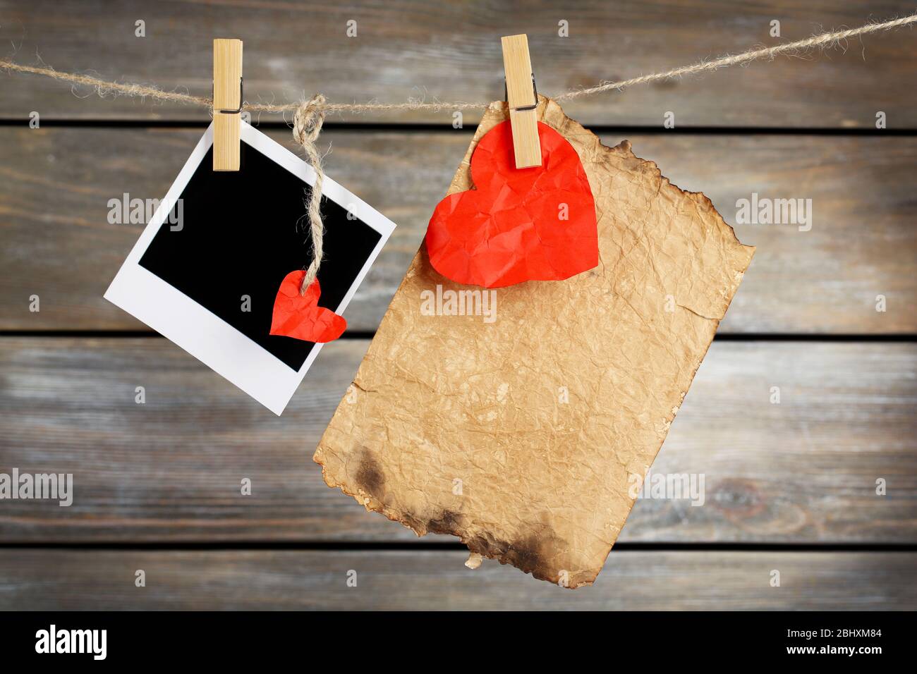 Bright hearts with card and photo paper hanging on rope on wooden ...
