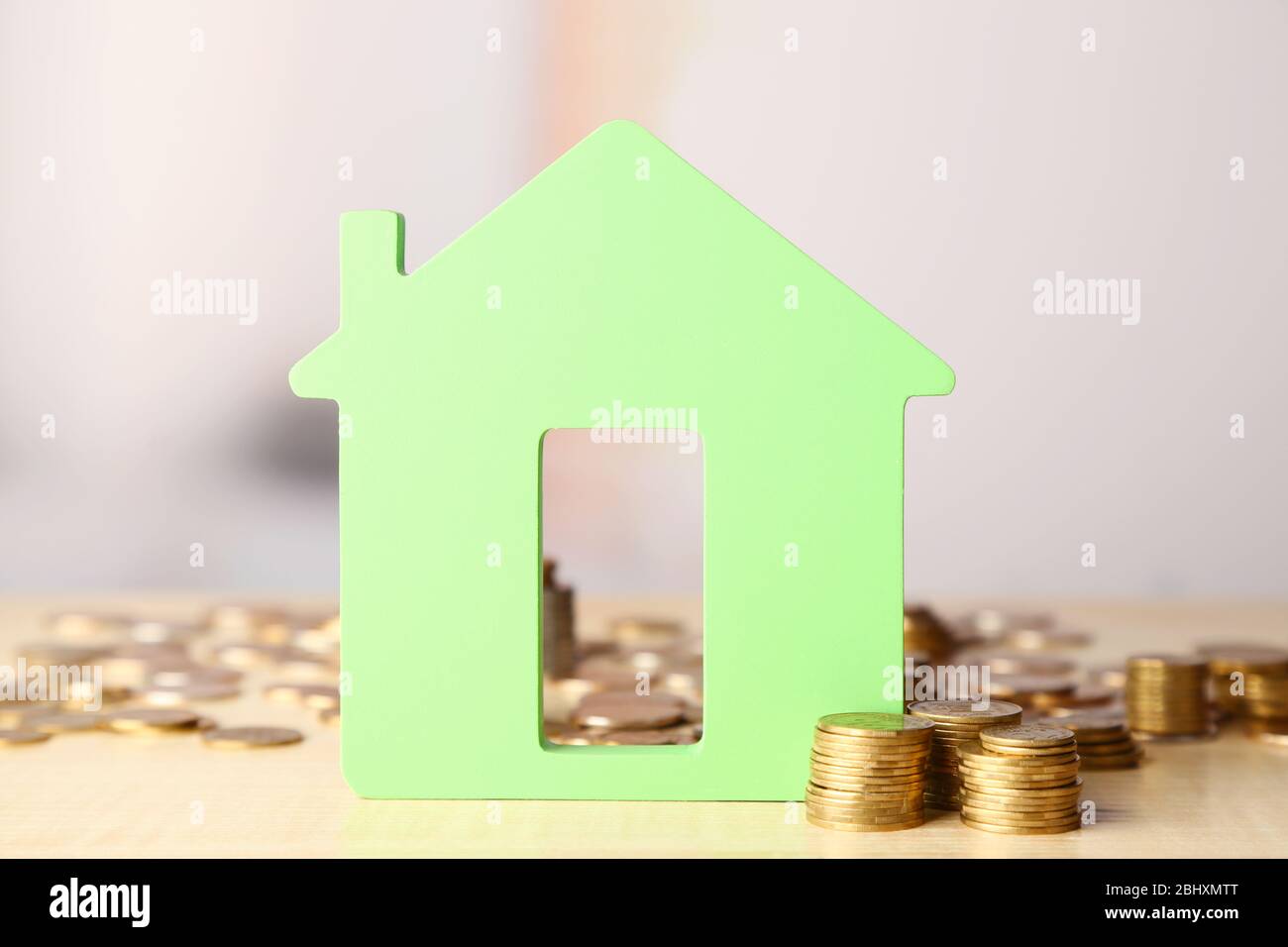 Model of house with coins on bright background Stock Photo - Alamy
