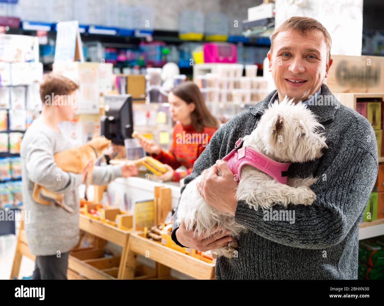 Cheerful friendly smiling positive man with dog near the cash desk in a ...