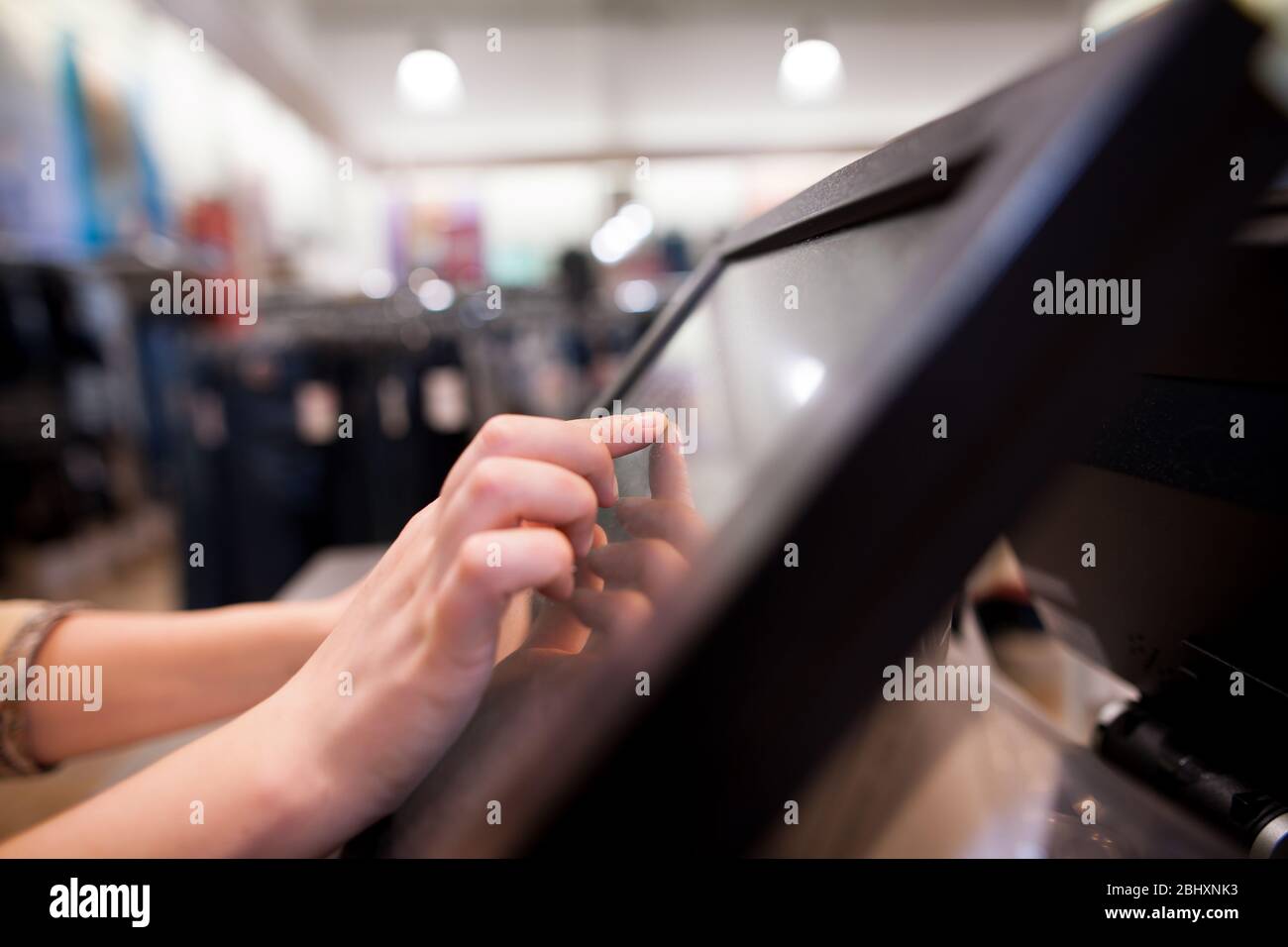 Young woman hand charging a payment for a some clothes by touchscreen ...