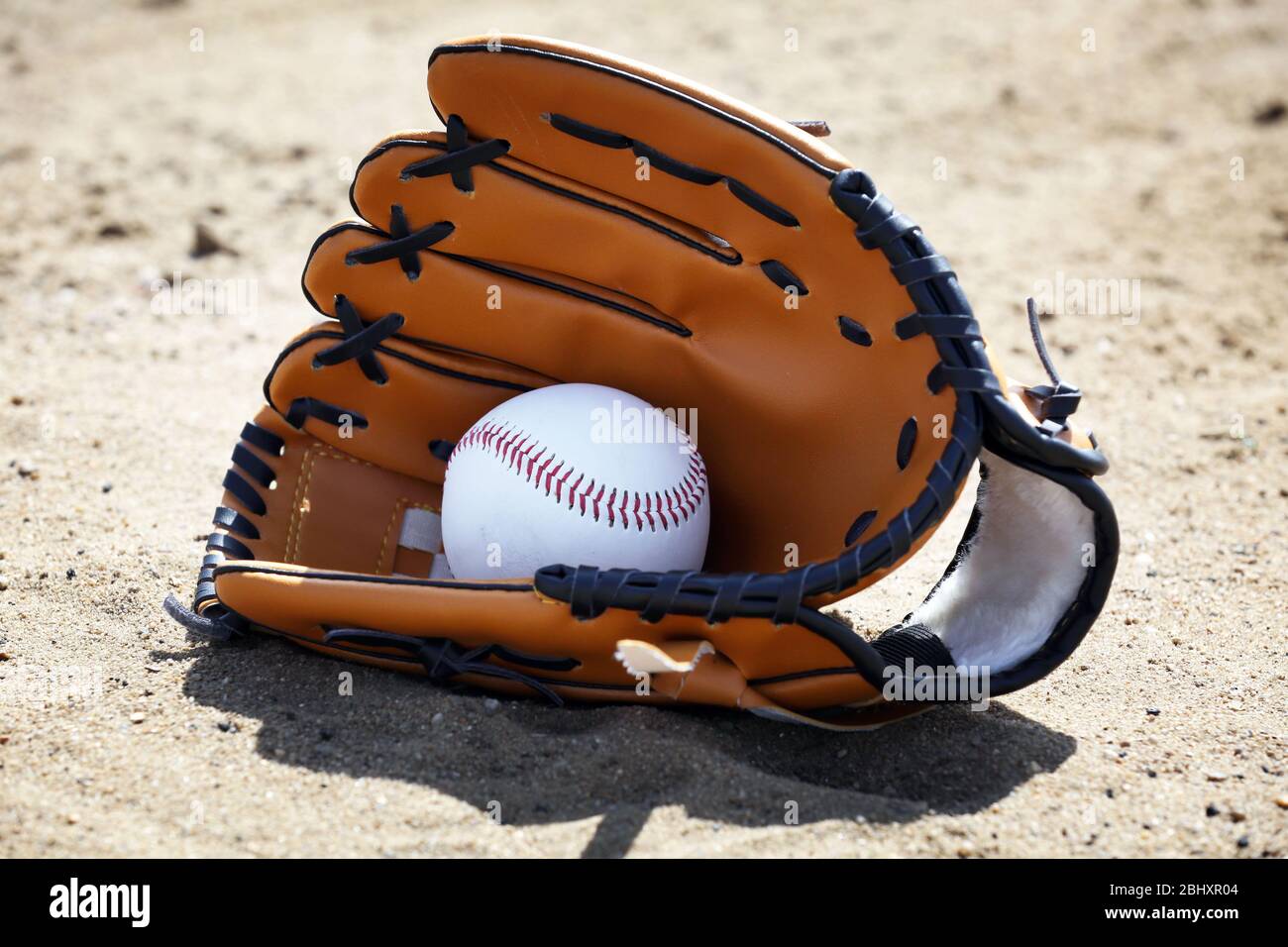 Baseball ball and glove on sand Stock Photo - Alamy