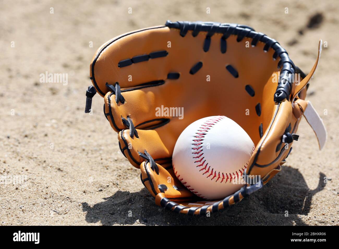 Baseball ball and glove on sand Stock Photo - Alamy