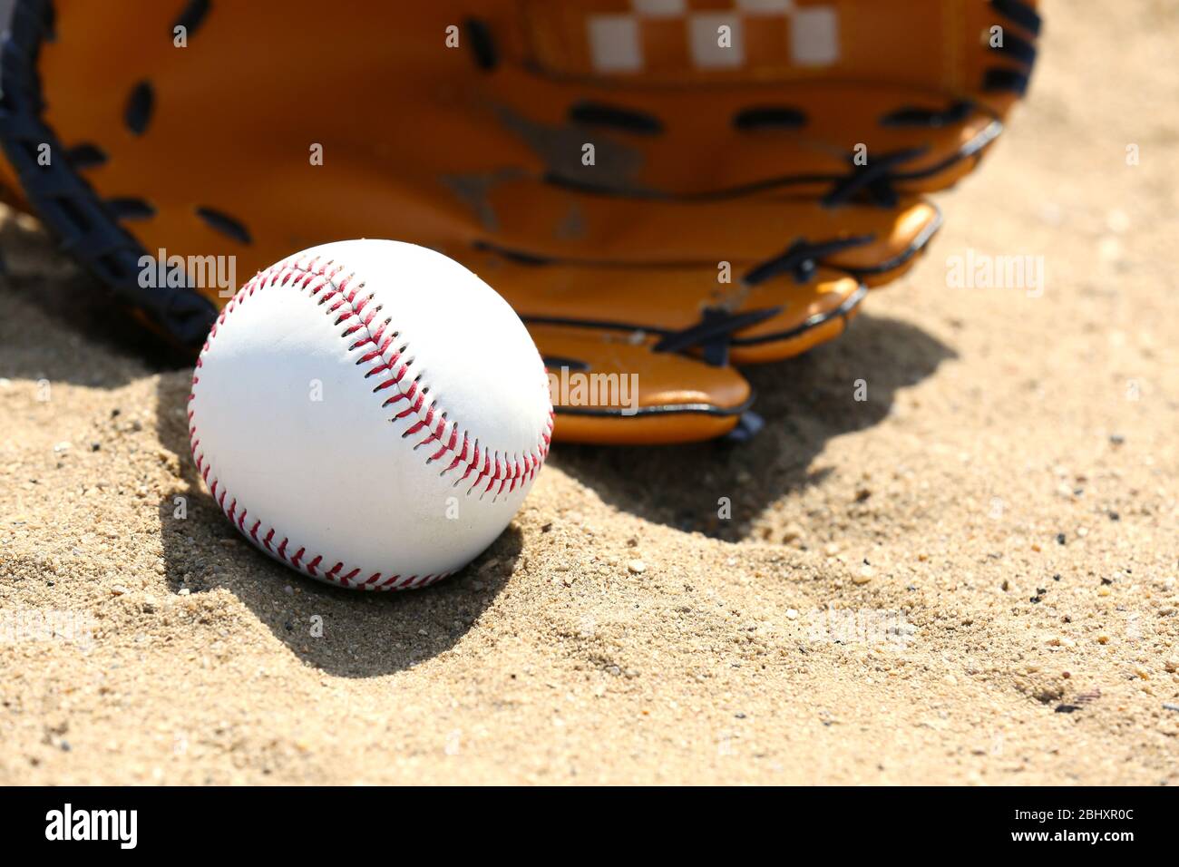 Baseball ball and glove on sand Stock Photo - Alamy