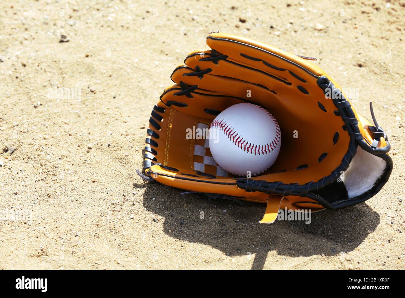 Baseball ball and glove on sand Stock Photo - Alamy