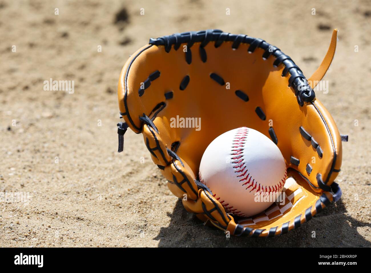 Baseball ball and glove on sand Stock Photo - Alamy