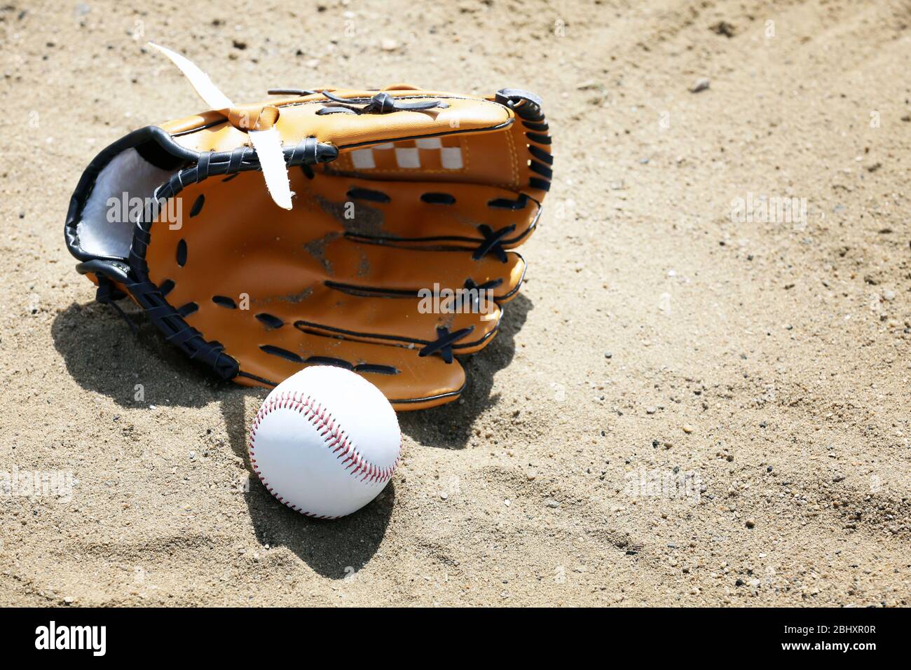 Baseball ball and glove on sand Stock Photo - Alamy