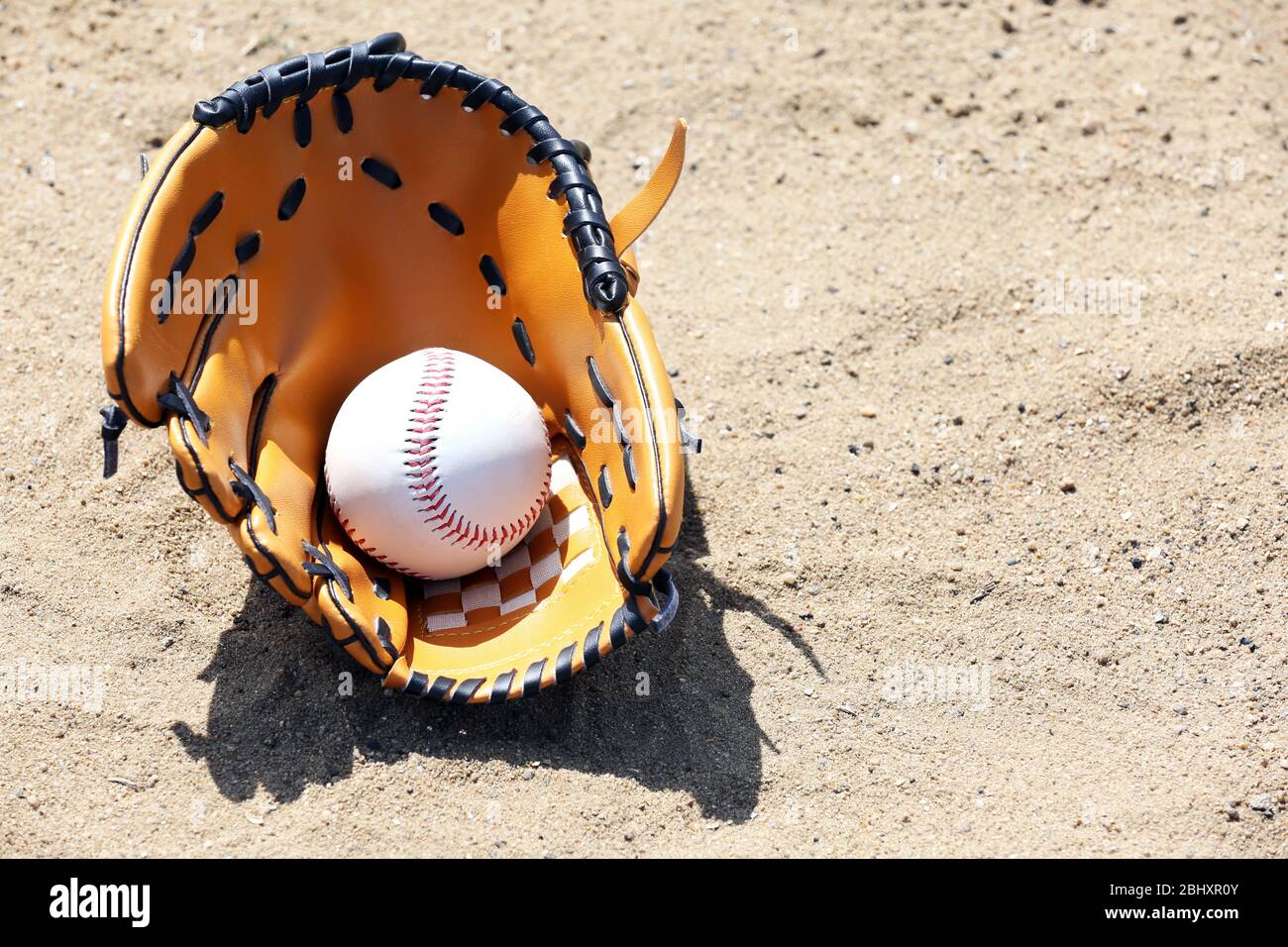 Baseball ball and glove on sand Stock Photo - Alamy