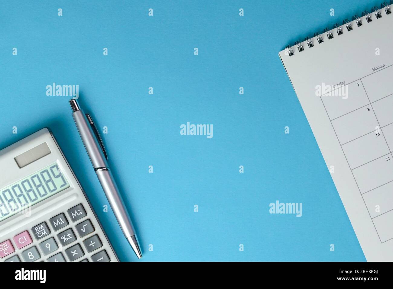 Calculator, pen and table calendar on blue background. Top view of ...