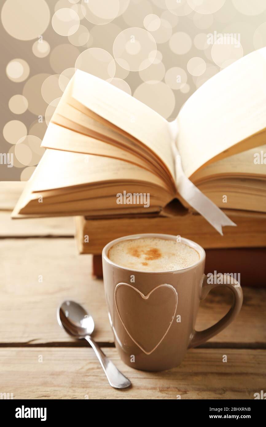 Cup of coffee with open book on bright background Stock Photo - Alamy