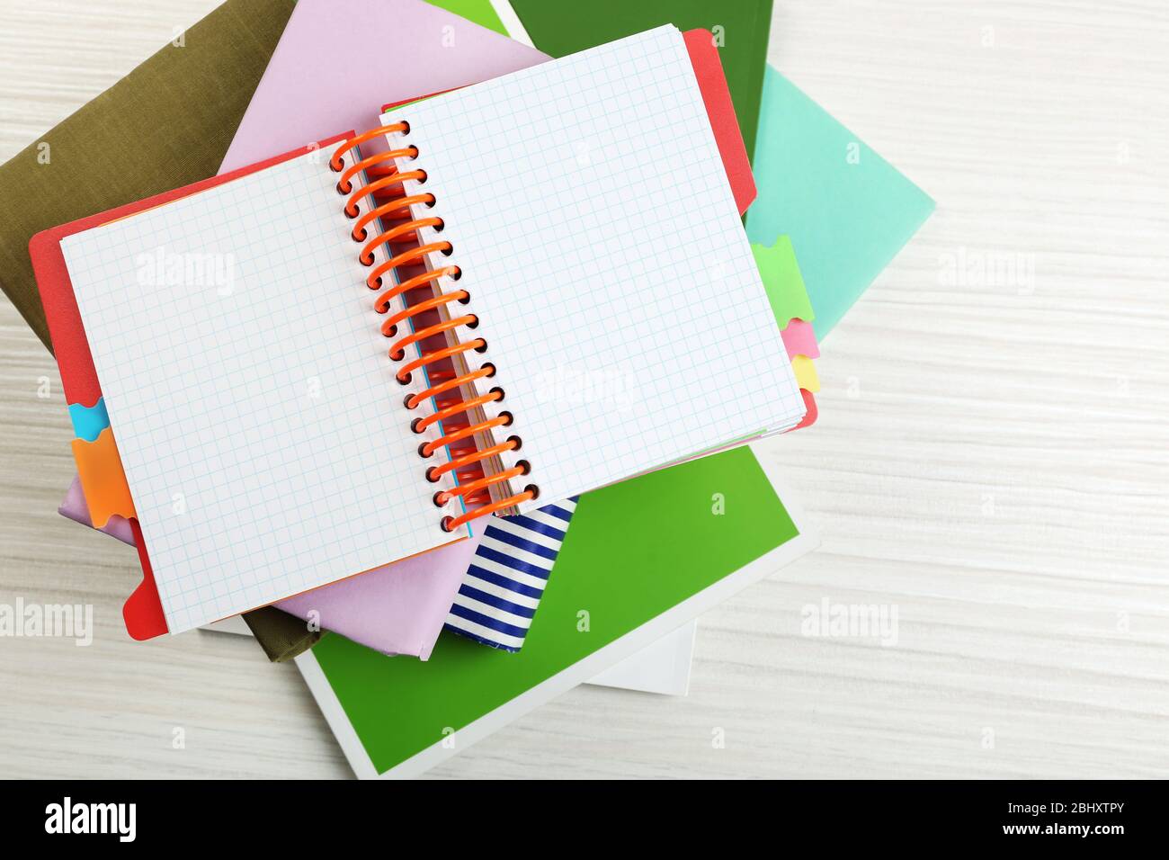 Notebook on top of pile of books and magazines on wooden background ...