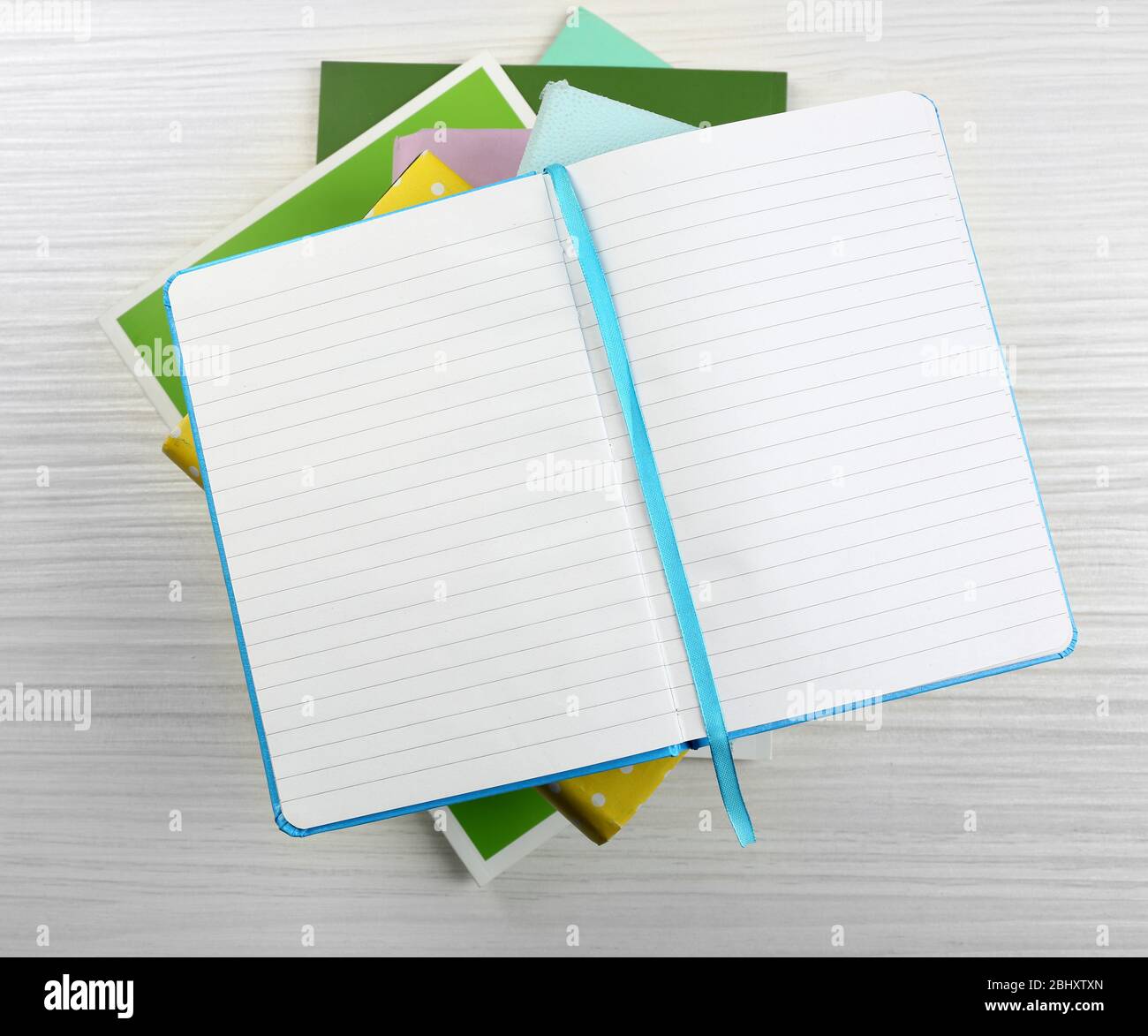Notebook on top of pile of books and magazines on wooden background ...