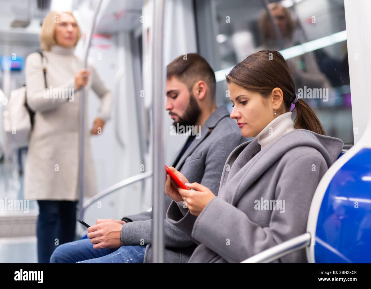 Positive woman reading from mobile phone screen in metro Stock Photo ...