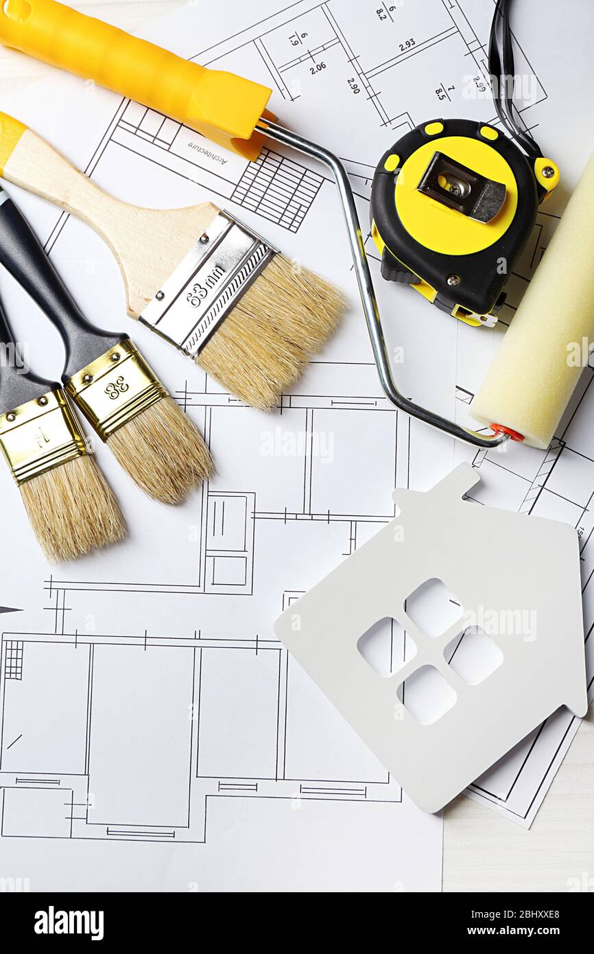 Construction instruments, plan and brushes on wooden table background ...