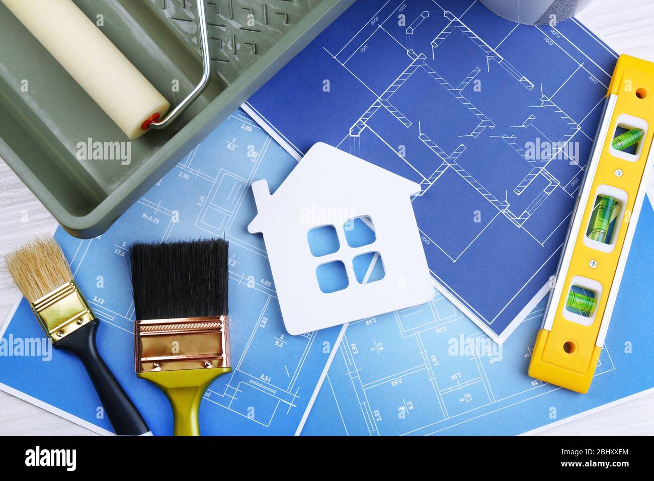 Construction instruments, plan and brushes over house plan on wooden ...