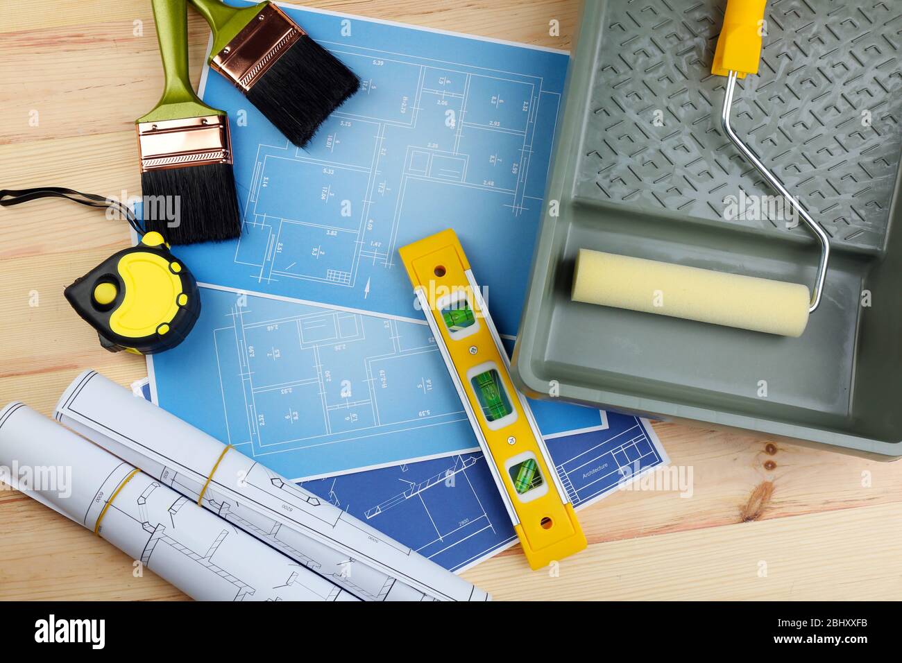 Construction instruments, plan and brushes on wooden table background ...