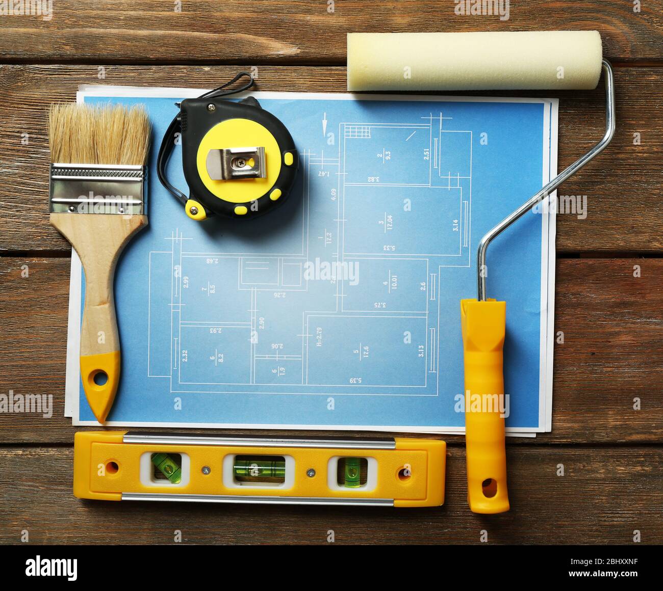 Construction instruments, plan and brushes on wooden table background ...
