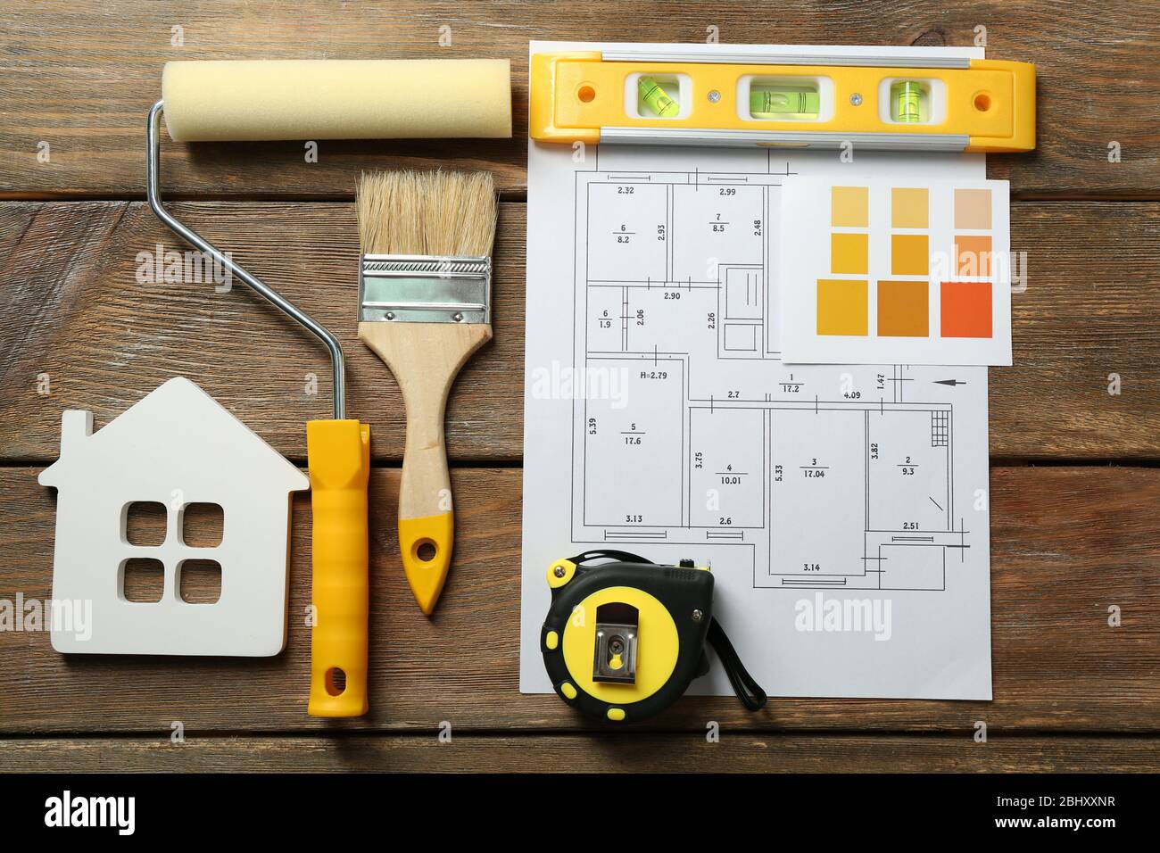 Construction instruments, plan and brushes on wooden table background ...
