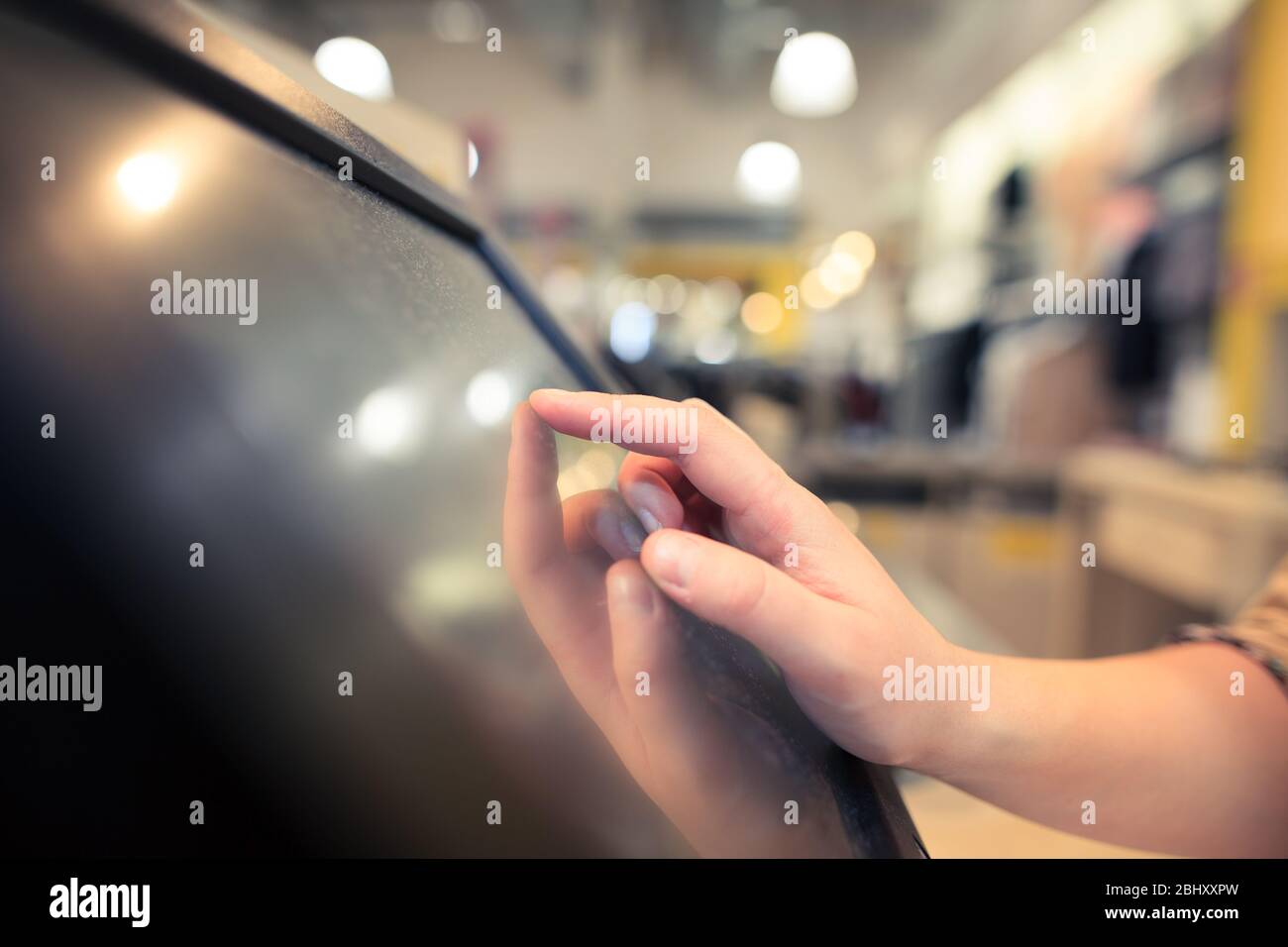 Young woman hand charging a payment for a some clothes by touchscreen ...