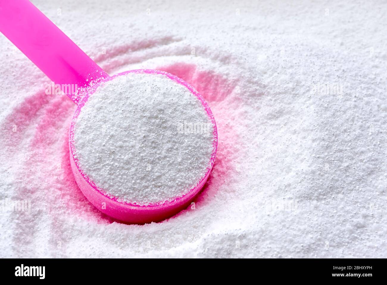 White laundry detergent powder for washing machine and pink plastic ...