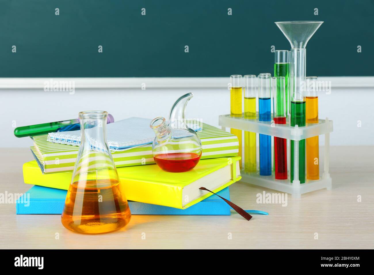 Desk in chemistry class with test tubes on green blackboard background ...