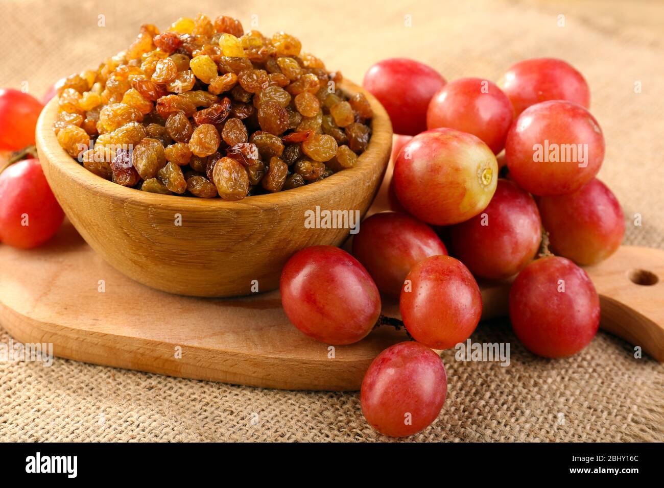 Raisins in bowl with grapes on table close up Stock Photo - Alamy