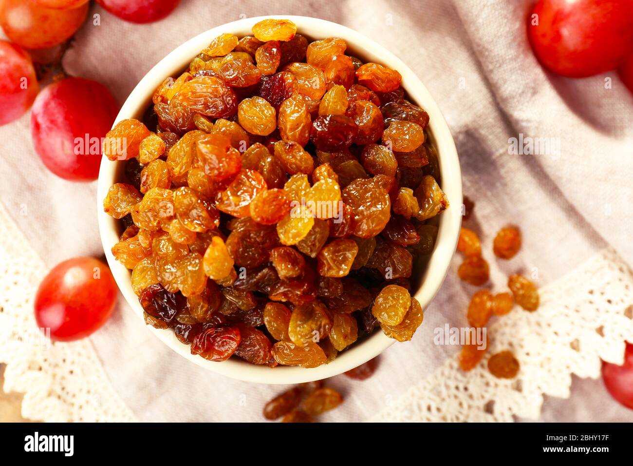 Raisins in bowl with grapes on table close up Stock Photo - Alamy