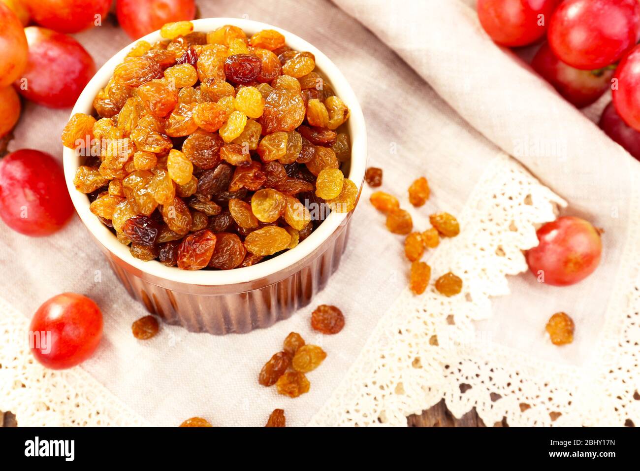 Raisins in bowl with grapes on table close up Stock Photo - Alamy